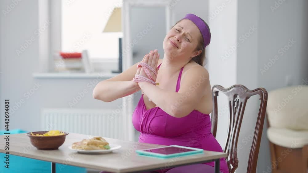 Portrait of depressed obese woman with hands wrapped with measuring ...