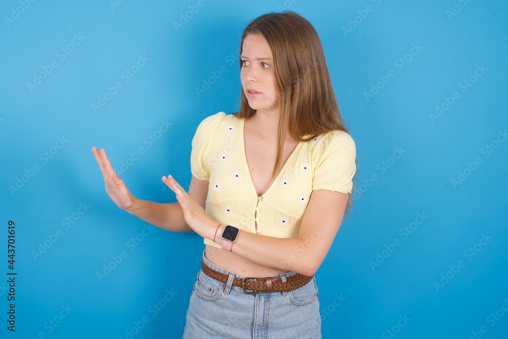 Displeased young beautiful blonde woman standing against blue ...