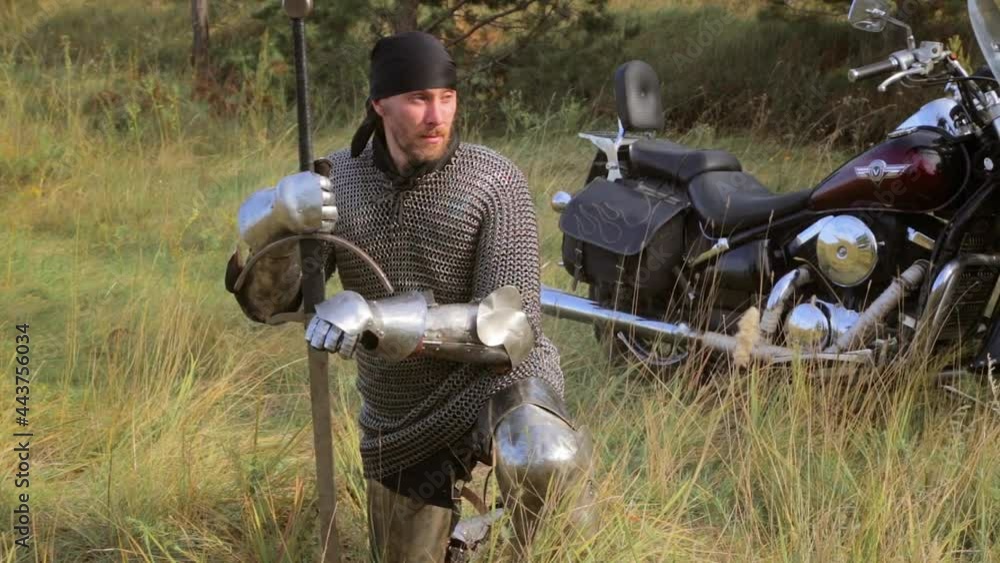 A knight in a full set of medieval armor and with a bandana on his head ...