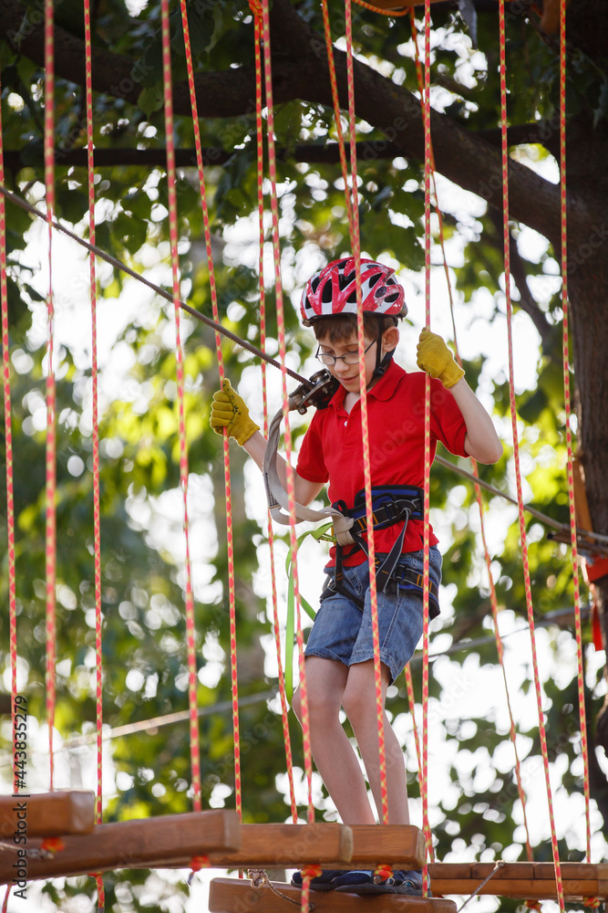 Boy In Adventure Park having fun in high wire park. Child climbs in a ...