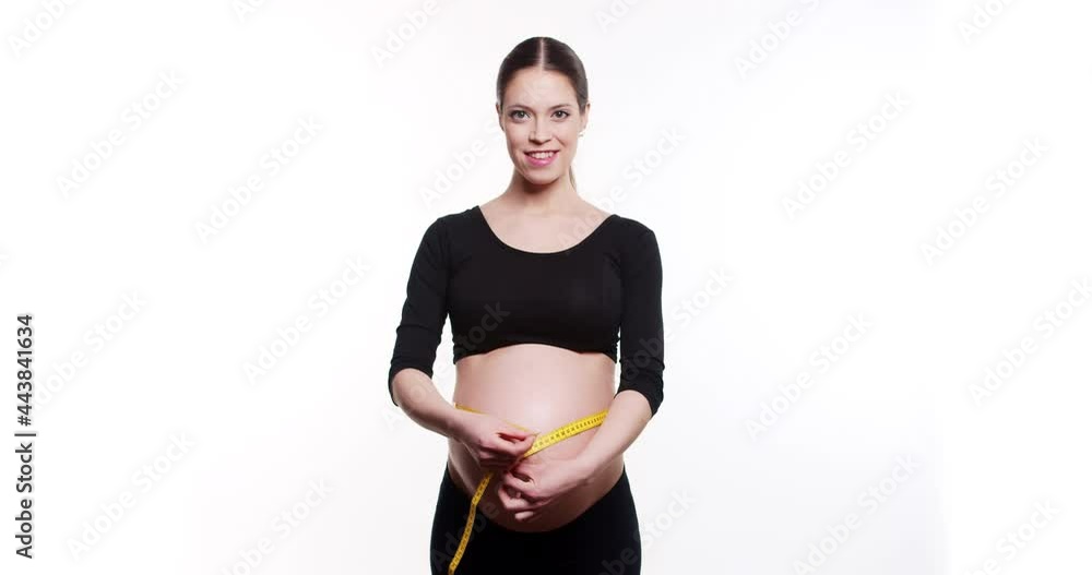 Beautiful body of pregnant caucasian young woman using measuring tape ...