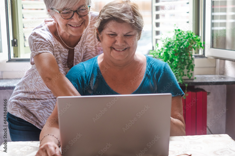 Two sisters or friends having fun using together the same laptop ...