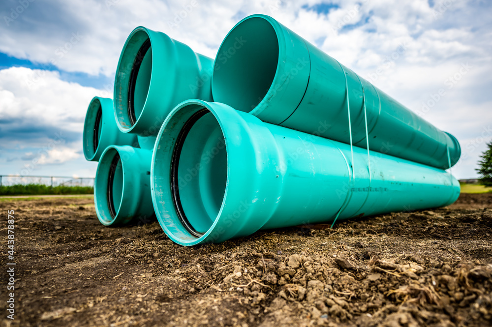 Stacked water main pipe with bell fitting next to an exposed trench for ...