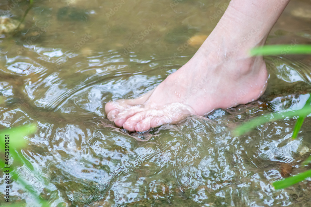Young boy playing barefoot with clear water at a little creek using his ...