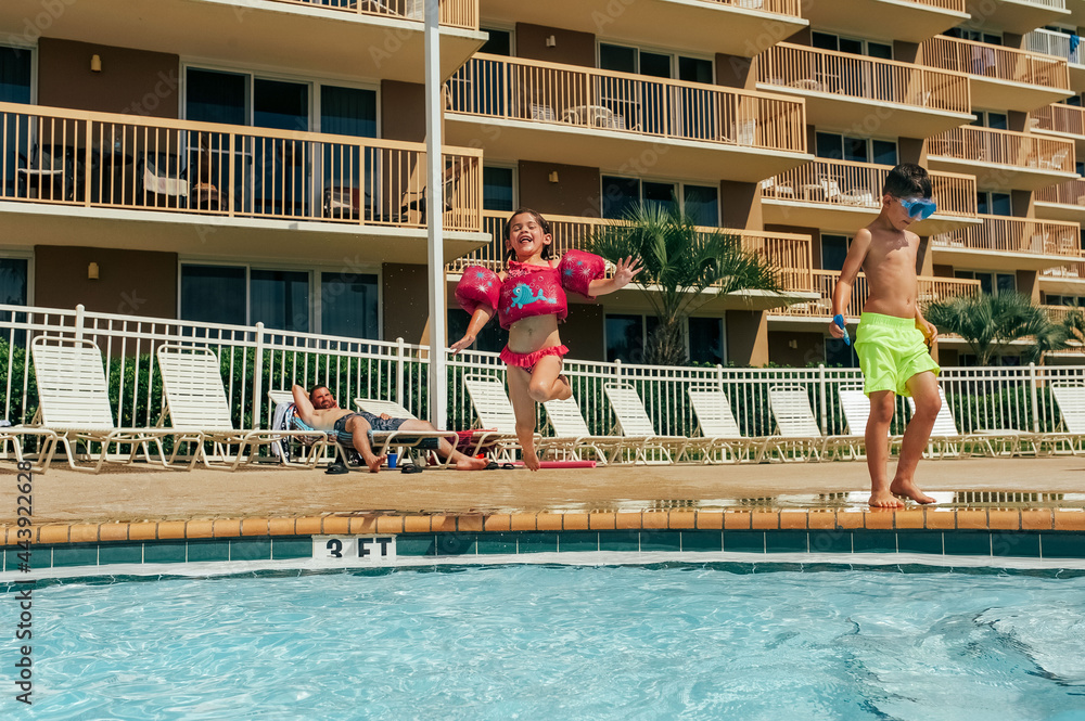 Girl running and jumping into the pool. Stock Photo | Adobe Stock