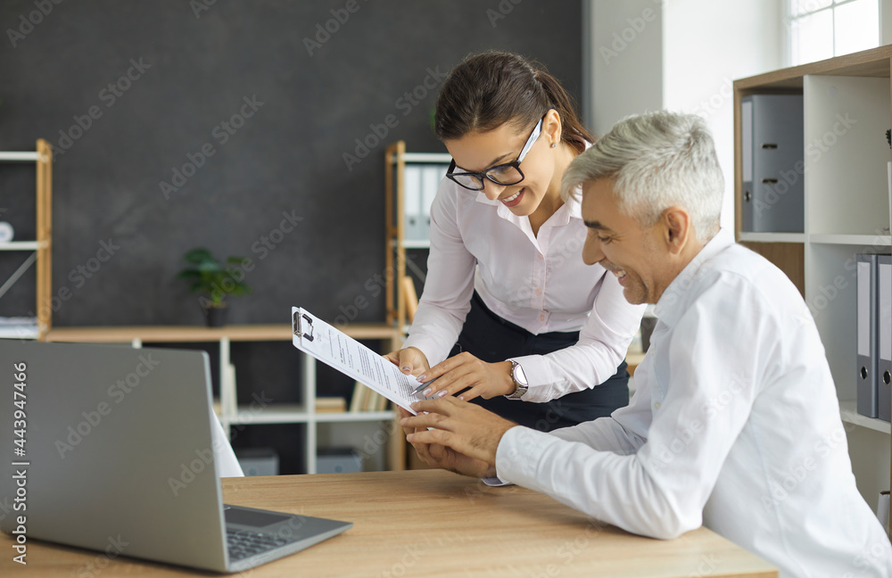 Smiling female secretary gives her senior manager paper documents or a ...