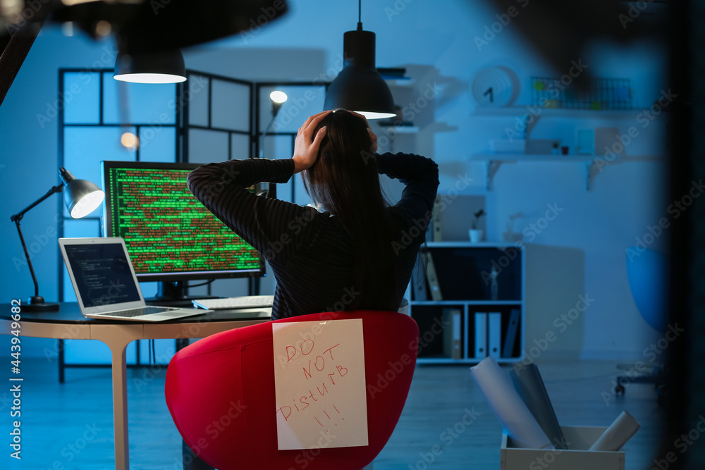 Female programmer working with computer and paper sheet with text DO ...