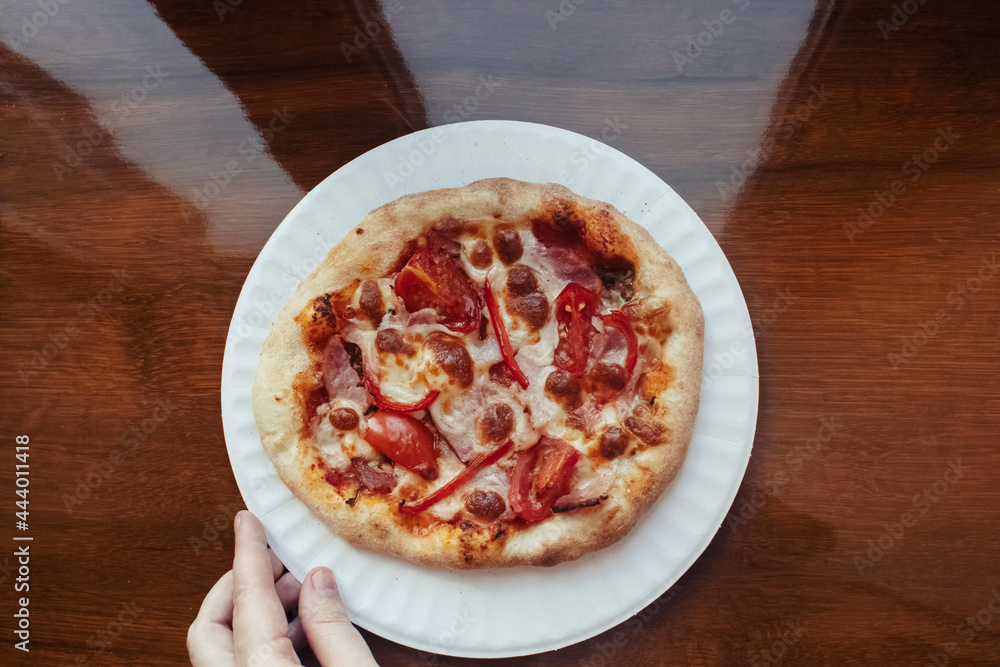 A close-up of a mini pizza in a disposable dish. Top view of takeaway ...