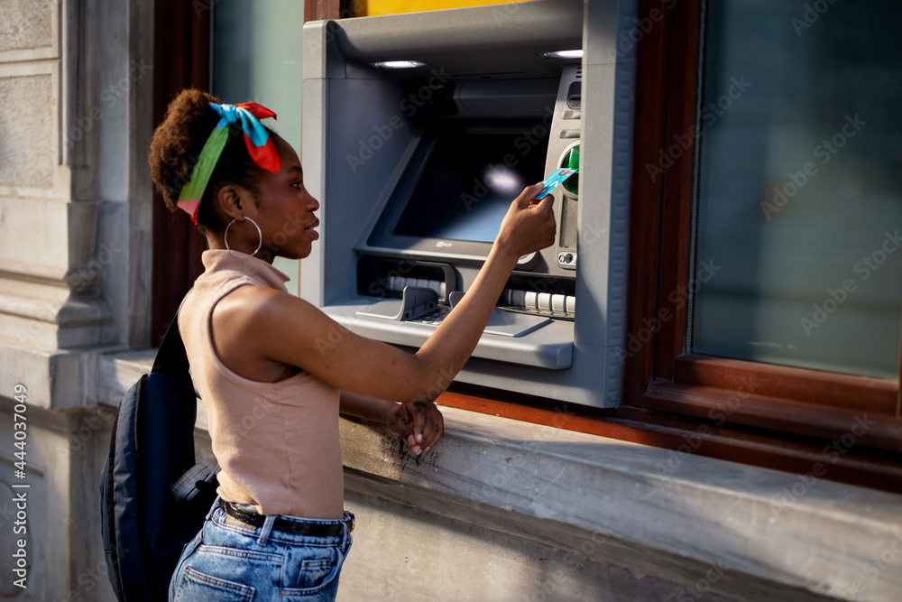 Beautiful african women using ATM machine. Attractive young woman ...