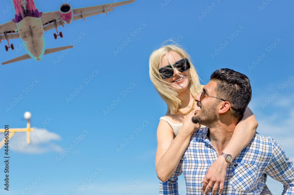 Smiling couple taking a pictures near airport with huge airplane flying ...