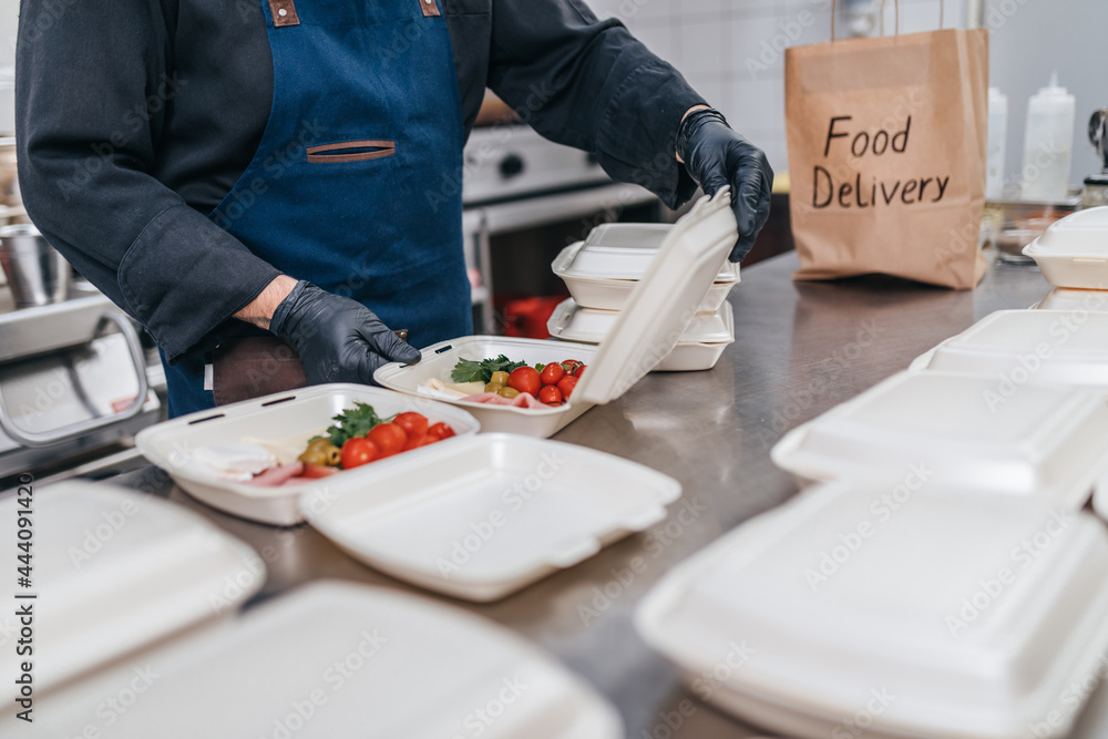 Food in disposable dishes ready for delivery. The chef prepares food in ...