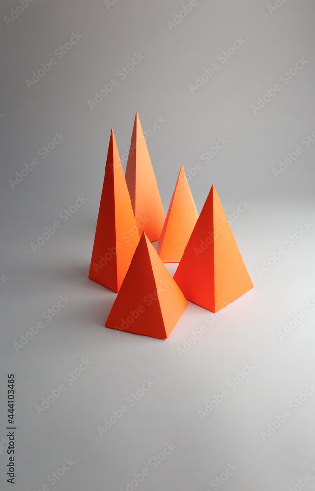 Orange papercraft pyramids on plain background Stock Photo | Adobe Stock