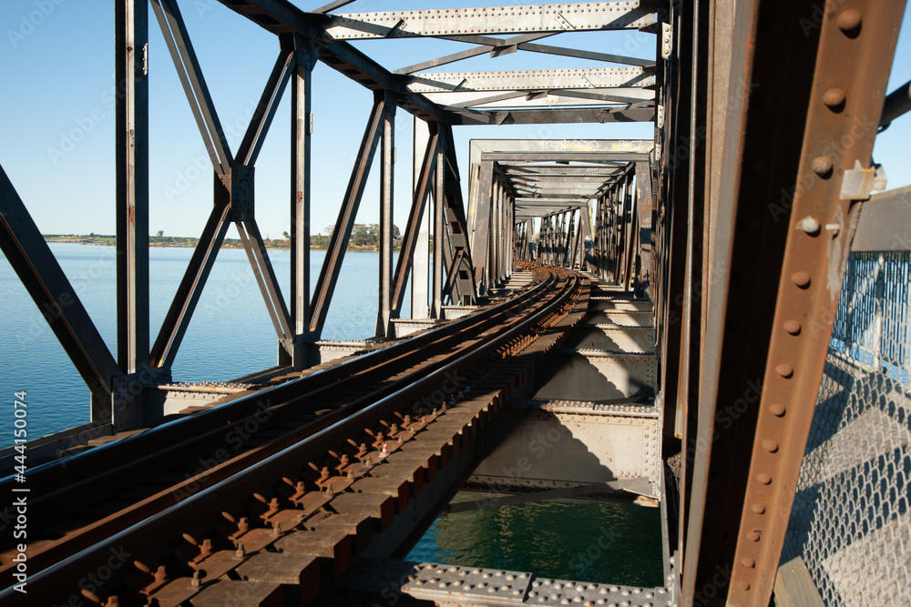 Rail lines lead and curve through the structure of steel truss bridge ...