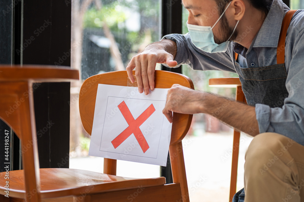 Asian waiter attach marks cross sign on the chair in the restaurant or ...