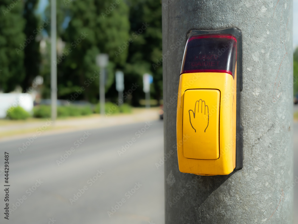 Large, bright yellow pedestrian crossing push button with hand sign on ...