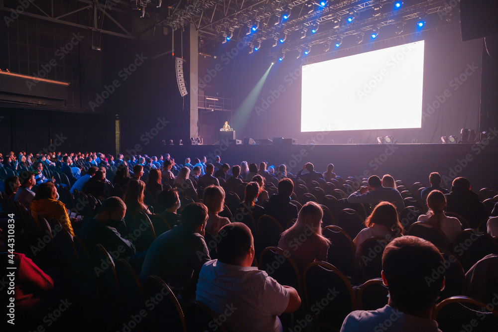 Audience sitting in front of stage with screen Stock Photo | Adobe Stock