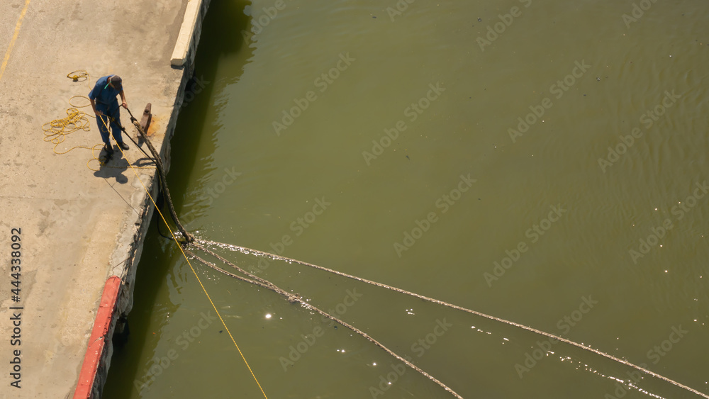 One mooring man stevedore pulling heavy mooring line during mooring of ...
