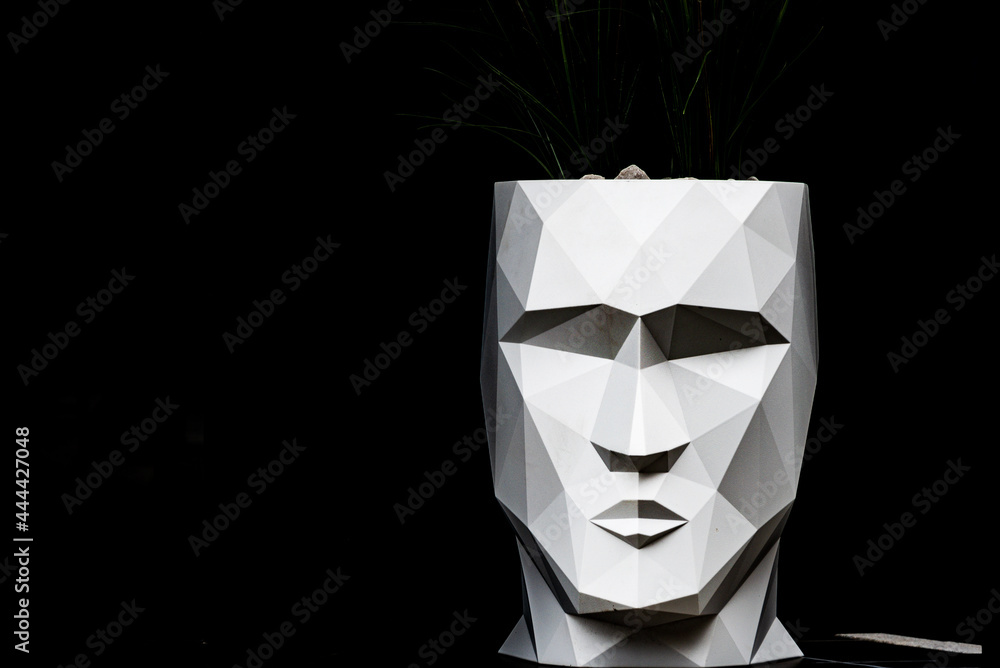 A white flower pot in the shape of a human face was made of triangular ...
