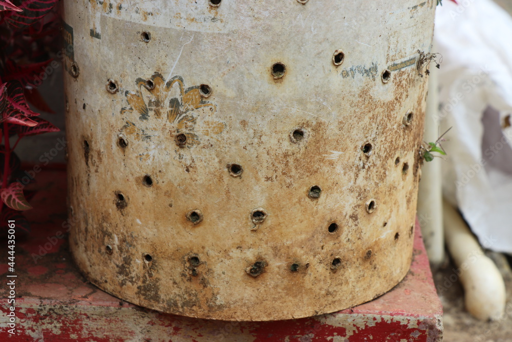 A plastic bucket filled with sand which is having holes in it used for ...