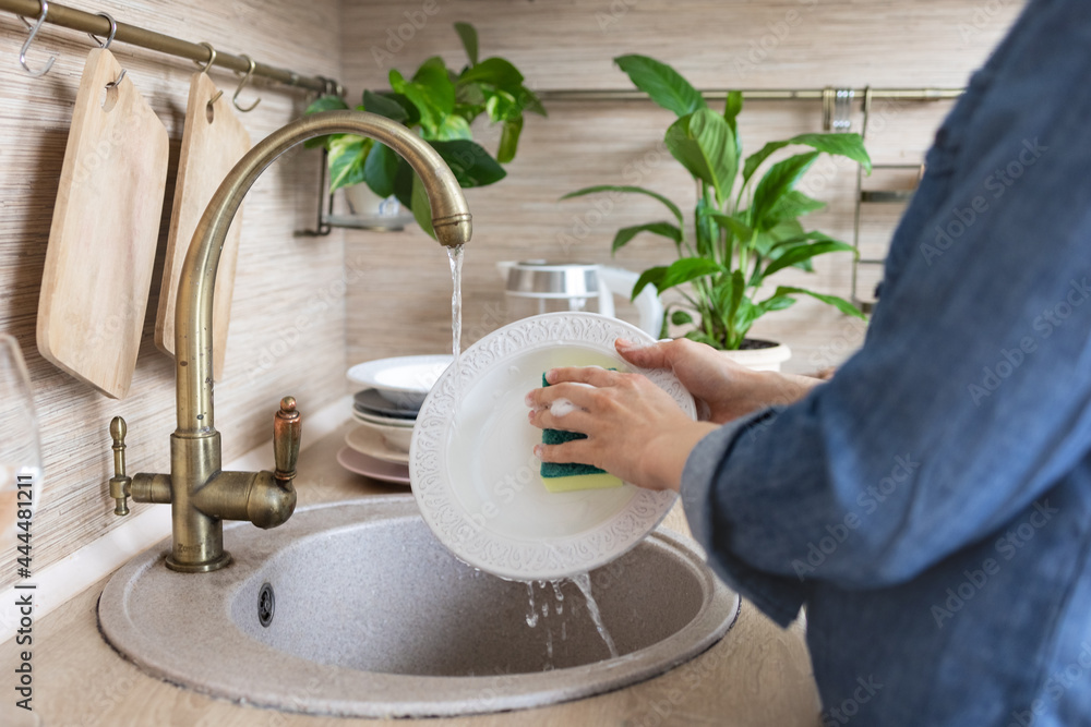 women's hands wash dishes in kitchen sink, woman cleans kitchen and ...