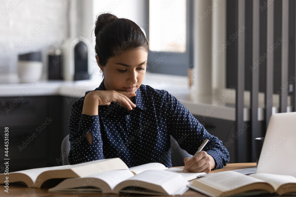 Focused millennial Indian student girl studying from home, preparing ...