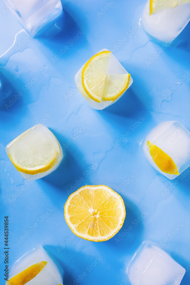 Modern geometric composition of the frozen slices of lemon and ice cubes on a blue background ...
