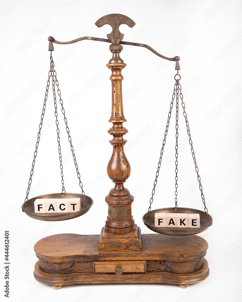 scale with the words fact and fake as symbol for the difference of both ...