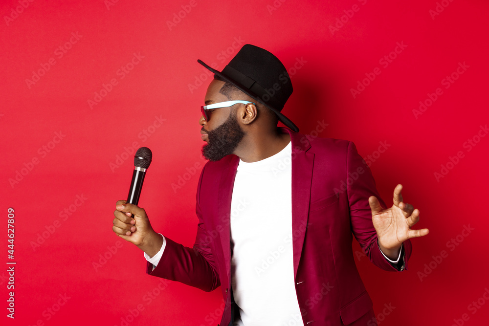 Passionate black male singer performing against red background, singing ...