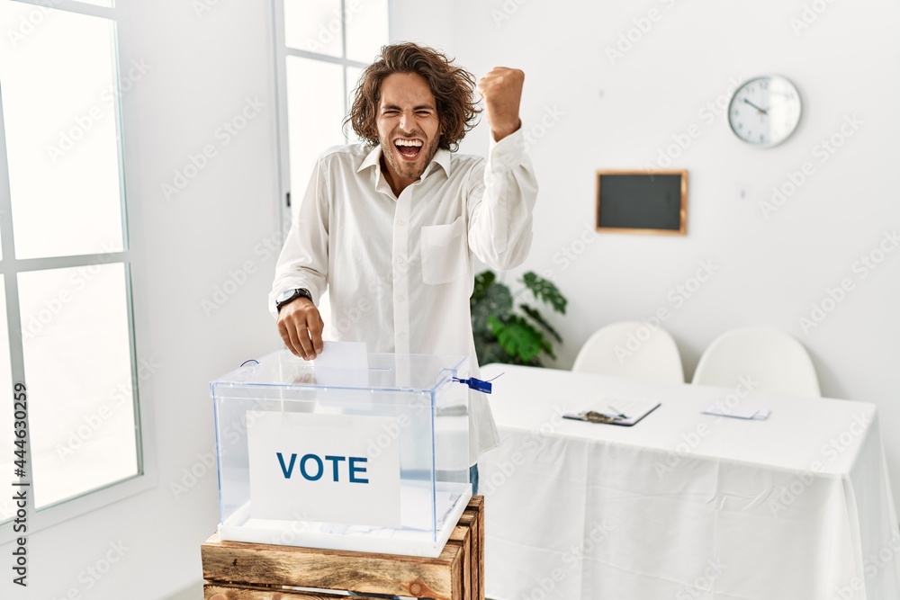 Young hispanic man voting putting envelop in ballot box angry and mad ...
