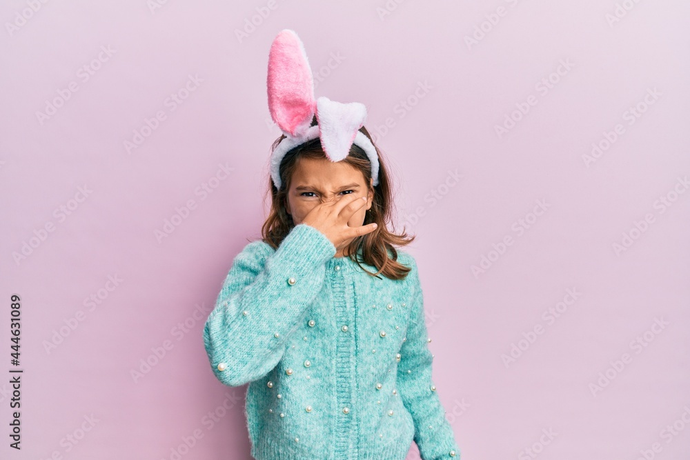 Little beautiful girl wearing cute easter bunny ears smelling something ...