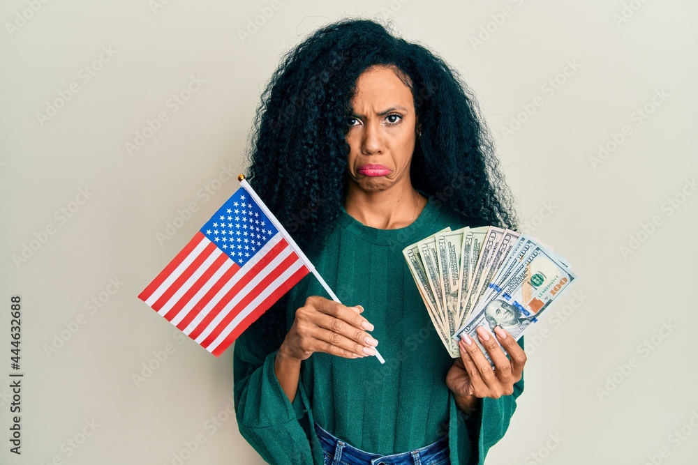 Middle age african american woman holding united states flag and ...