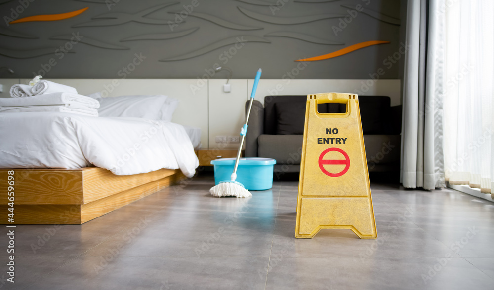 A yellow "NO ENTRY" sign place on the floor in hotel room. While ...