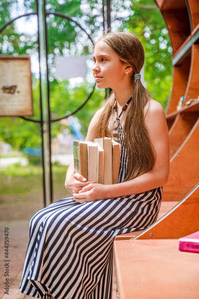 Cute little girl in the library in the park holding books. Togliatti ...