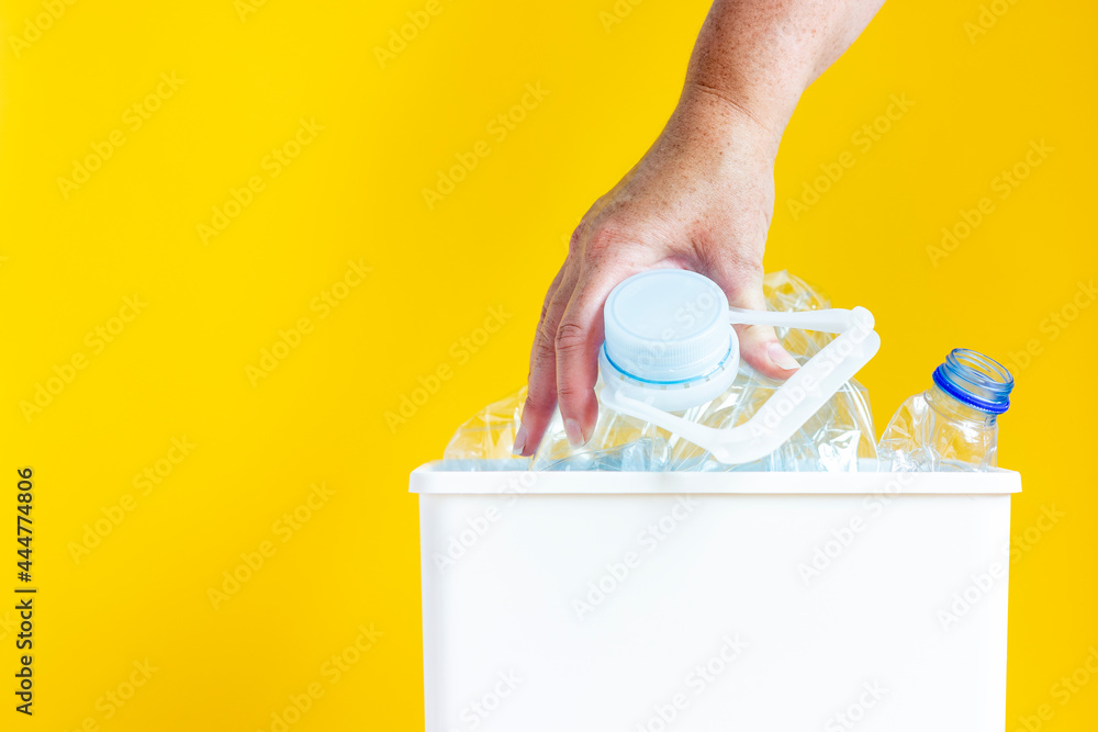 Woman's hand squeezing empty bottles and other plastic waste in a trash ...