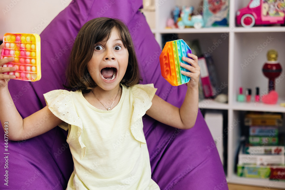 Little girl is playing pop it simple dimple snapperz toy. Colorful and ...