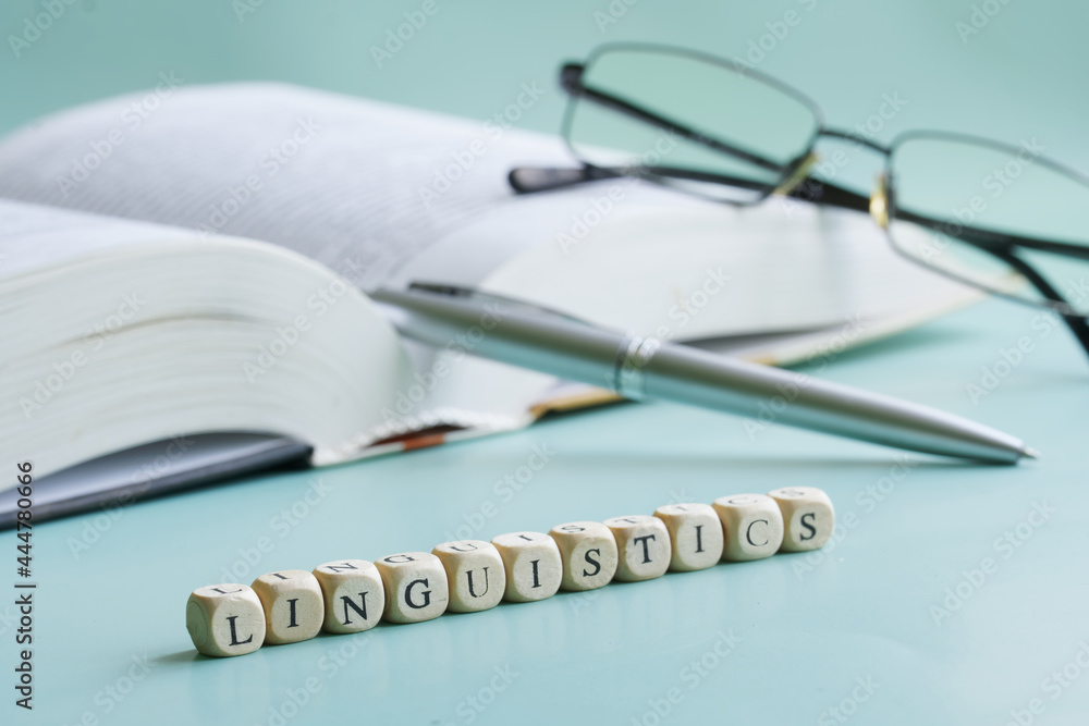 The word linguistics next to an open book, a fountain pen and ...