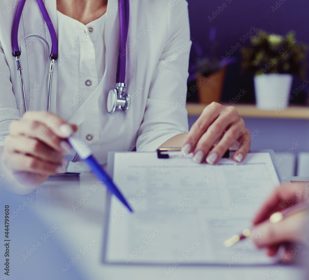 Doctor and patient examining a file with medical records, she is ...