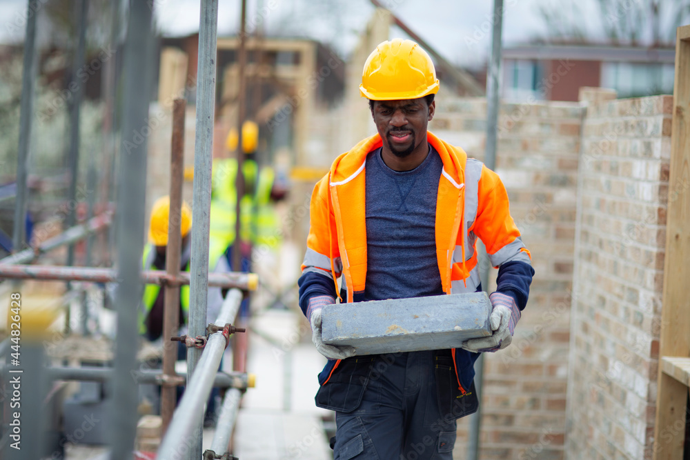 Male construction worker carrying brick at construction site Stock ...