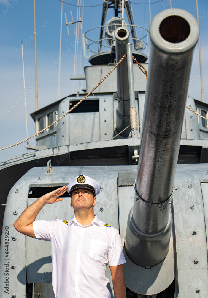 A navy officer standing under a ship's cannon and do salute.The captain ...