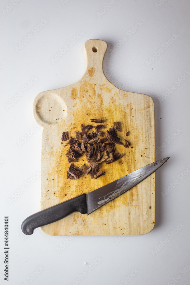 Trozos de carne asada en tabla de picar de madera con cuchillo en fondo ...