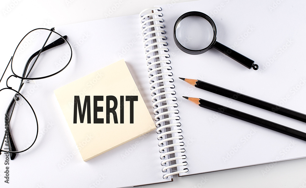 Text MERIT on the sticker with keyboard , pencils and office tools ...