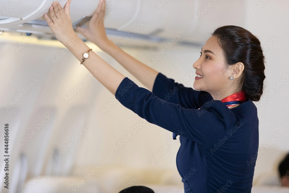 flight attendant checking and closing cabin compartment in airplane ...