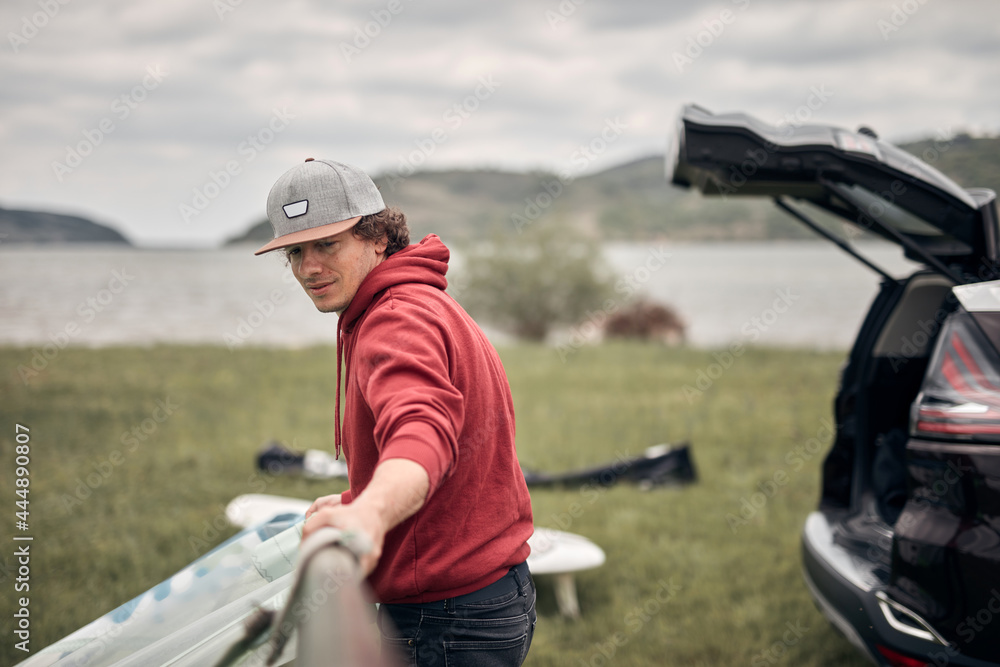 Windsurfer and camper packing and unpacking from a car's roof rack in ...