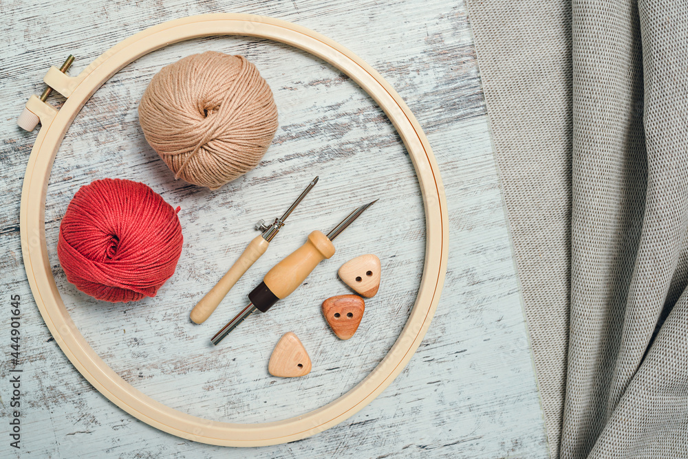 Layout of stretching hoop, punch needles, balls of yarn and wooden ...