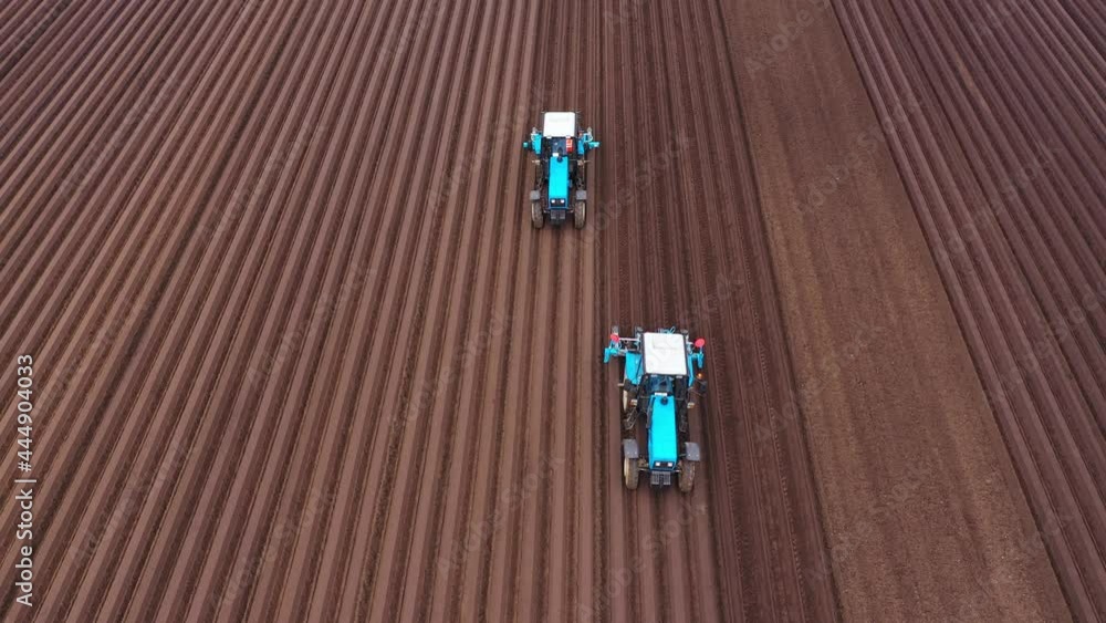 Tractor sowing seeds with a seeder driller in a field. Top view of ...