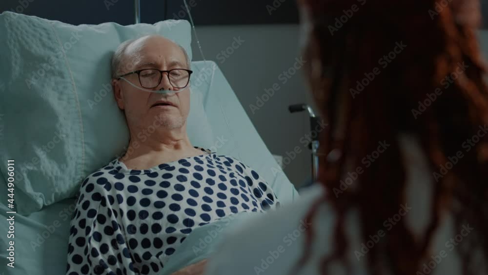 Sick elder patient talking to african american doctor in hospital ward ...