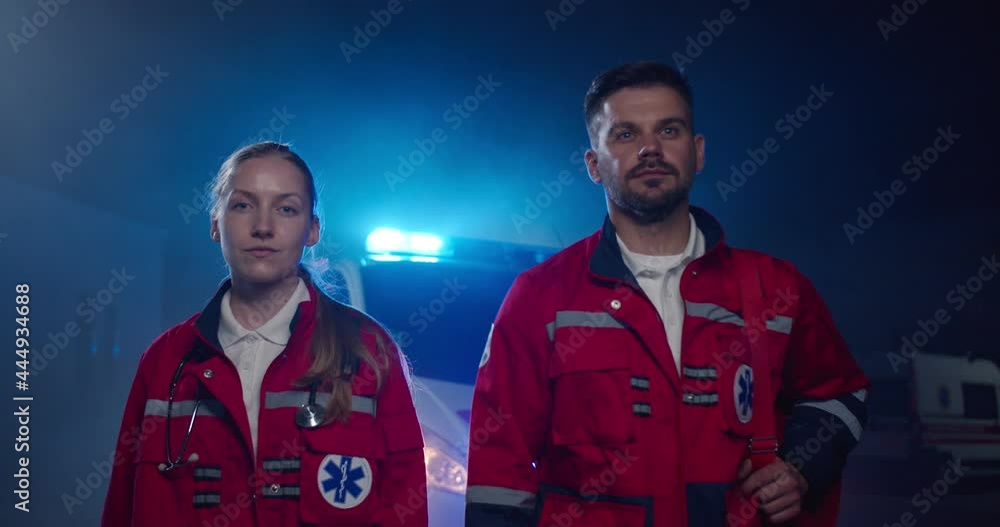 Couple of paramedics walking fast to ambulance car at night shift ...