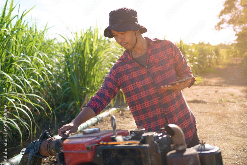 Farmer checking pump in sugar cane farm. Smart young farmers use ...