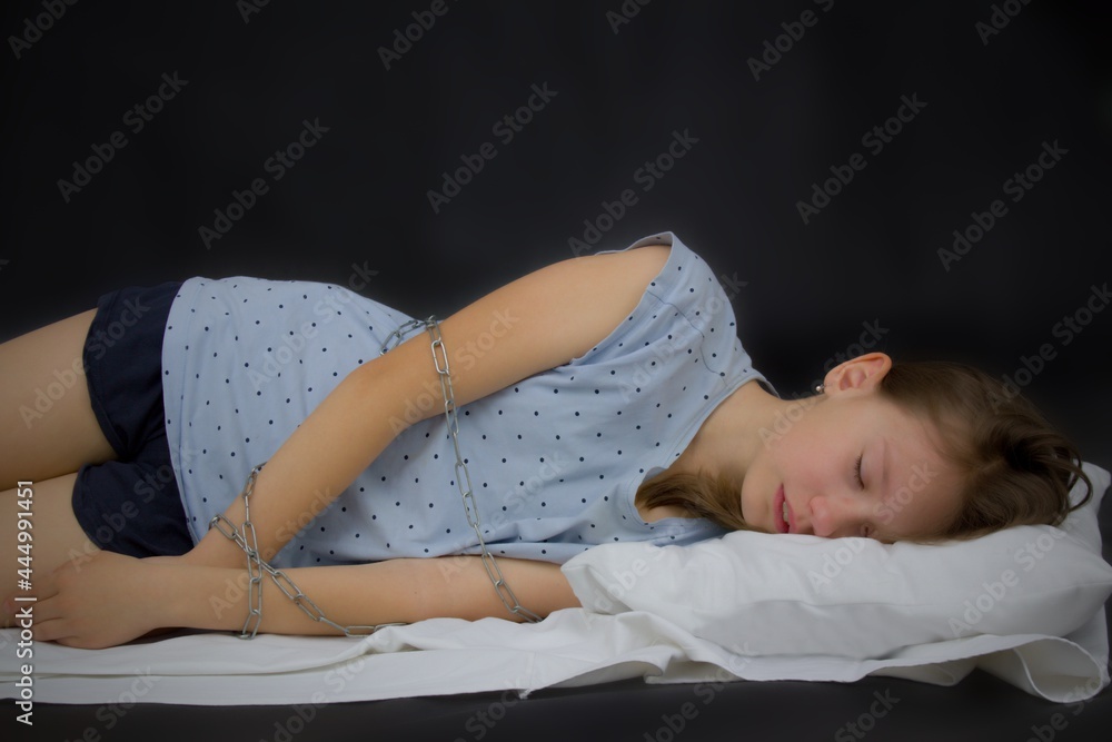 The little girl is lying in bed. She is chained.The sleeping girl is ...