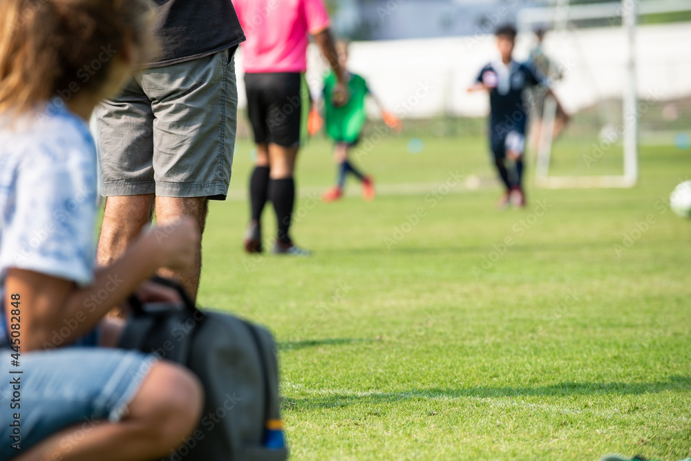 Mother and father watching their son playing football in a school ...
